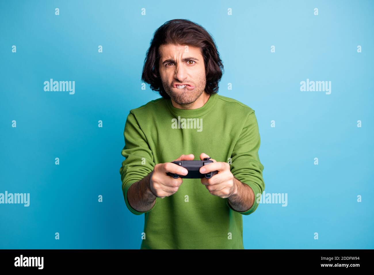 Photo of crazy tense guy hold gamepad funny look camera bite lip wear ...