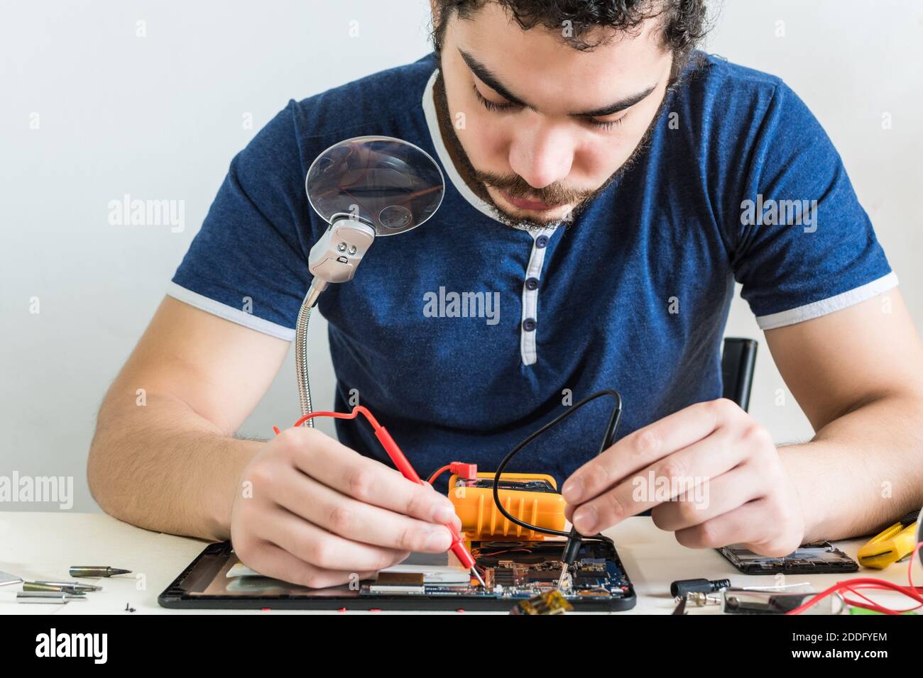 A repairman testing the electric circuit of a tablet. Young repairman ...