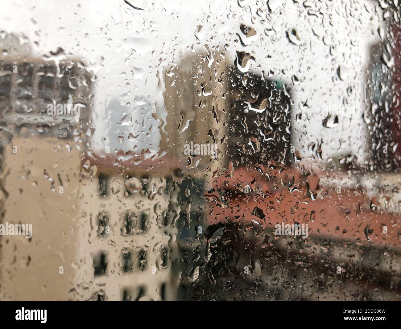 background with rain drops on window pane against buildings in a rainy ...