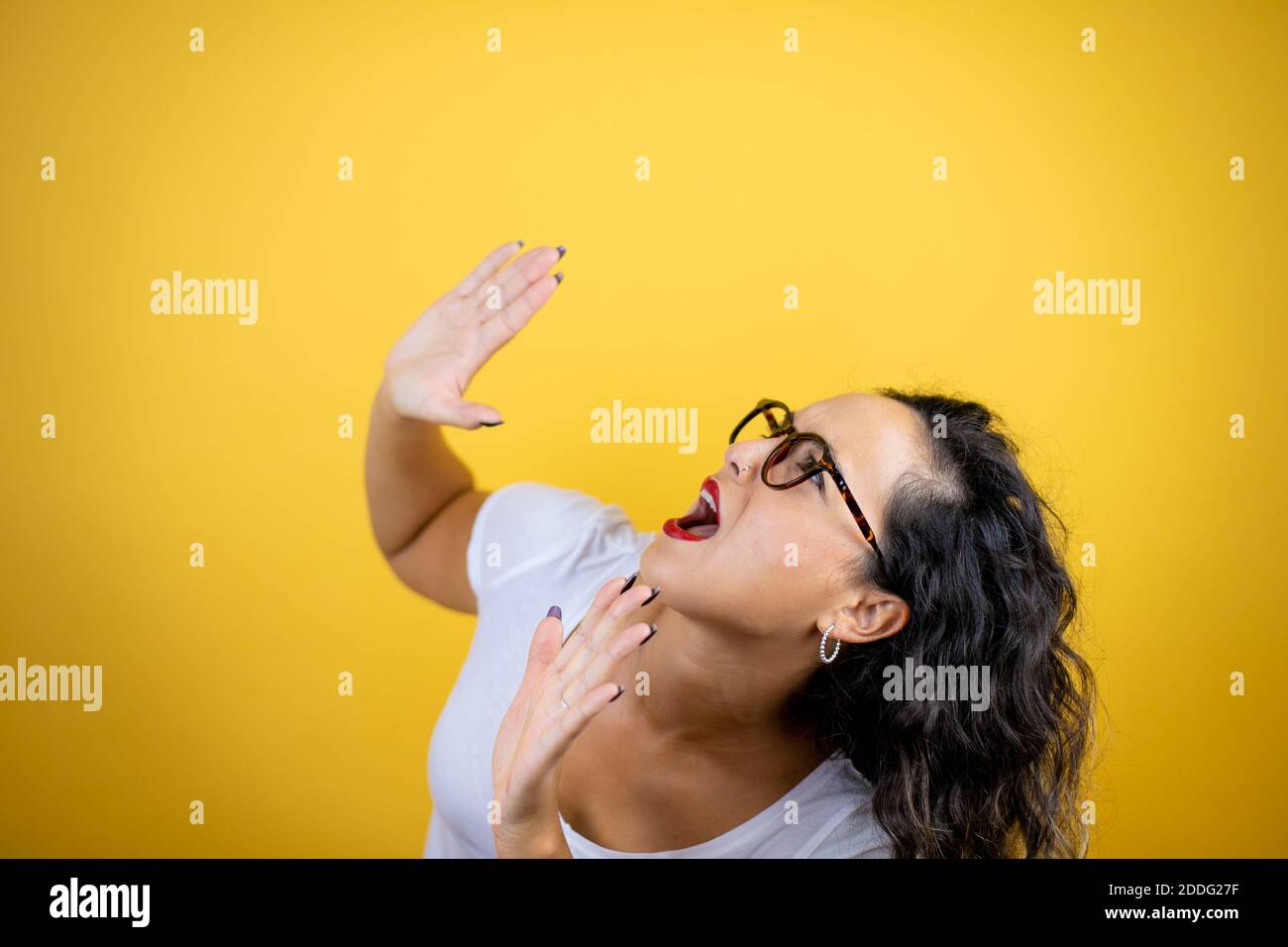 Young beautiful woman wearing casual white t-shirt over isolated yellow ...