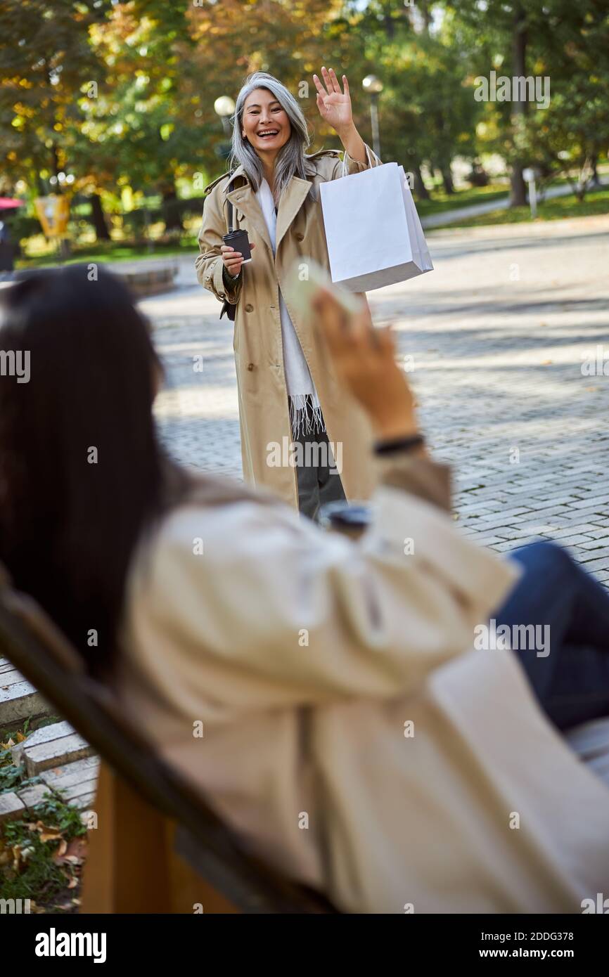 Cheerful woman saying hello to friend on the street Stock Photo - Alamy