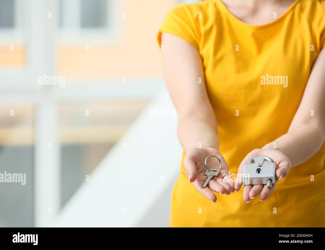Woman with key and padlock indoors Stock Photo - Alamy
