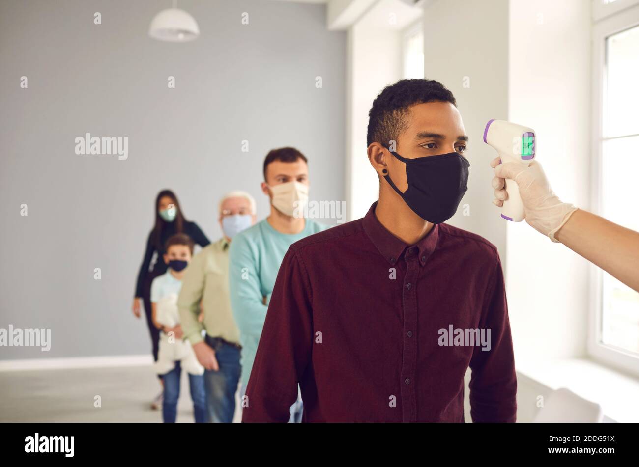 Man, standing in line in public place, gets his body temperature ...