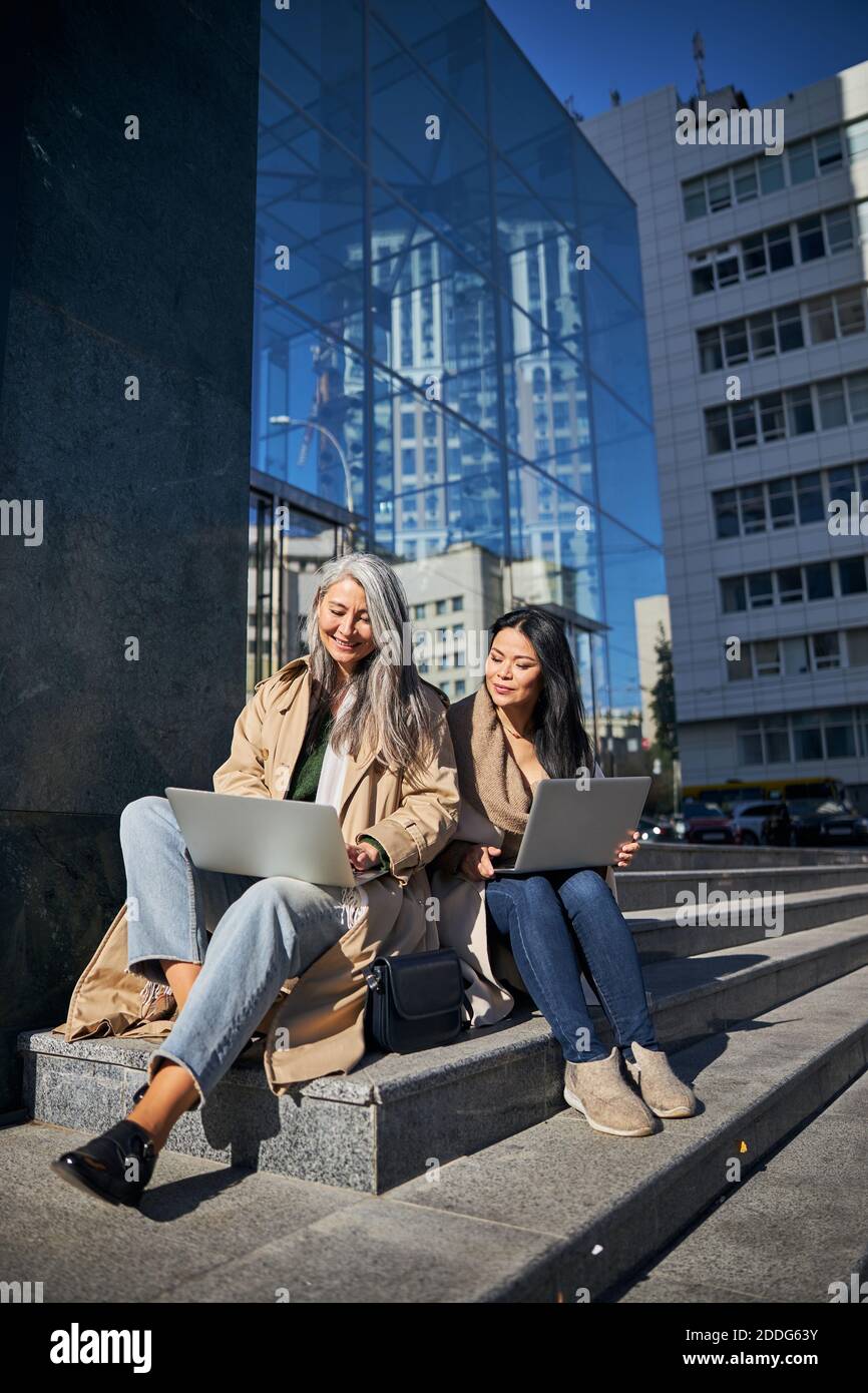 Two beautiful women using modern laptops outdoors Stock Photo - Alamy
