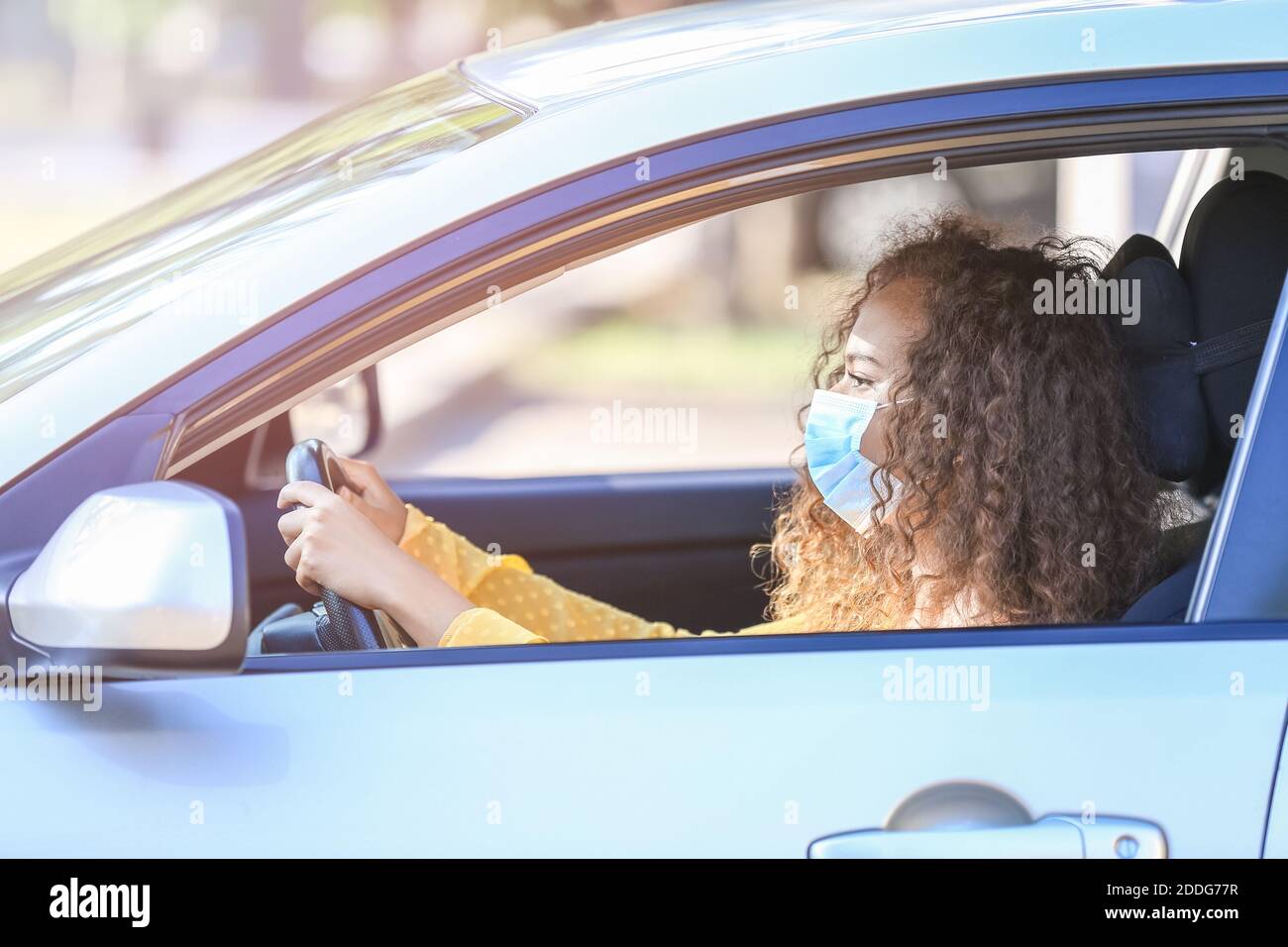 African-American woman wearing medical mask while driving car Stock ...