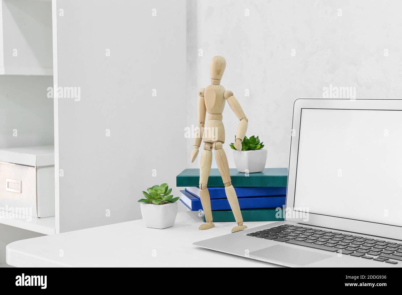 Modern workplace with laptop and wooden mannequin in office Stock Photo ...