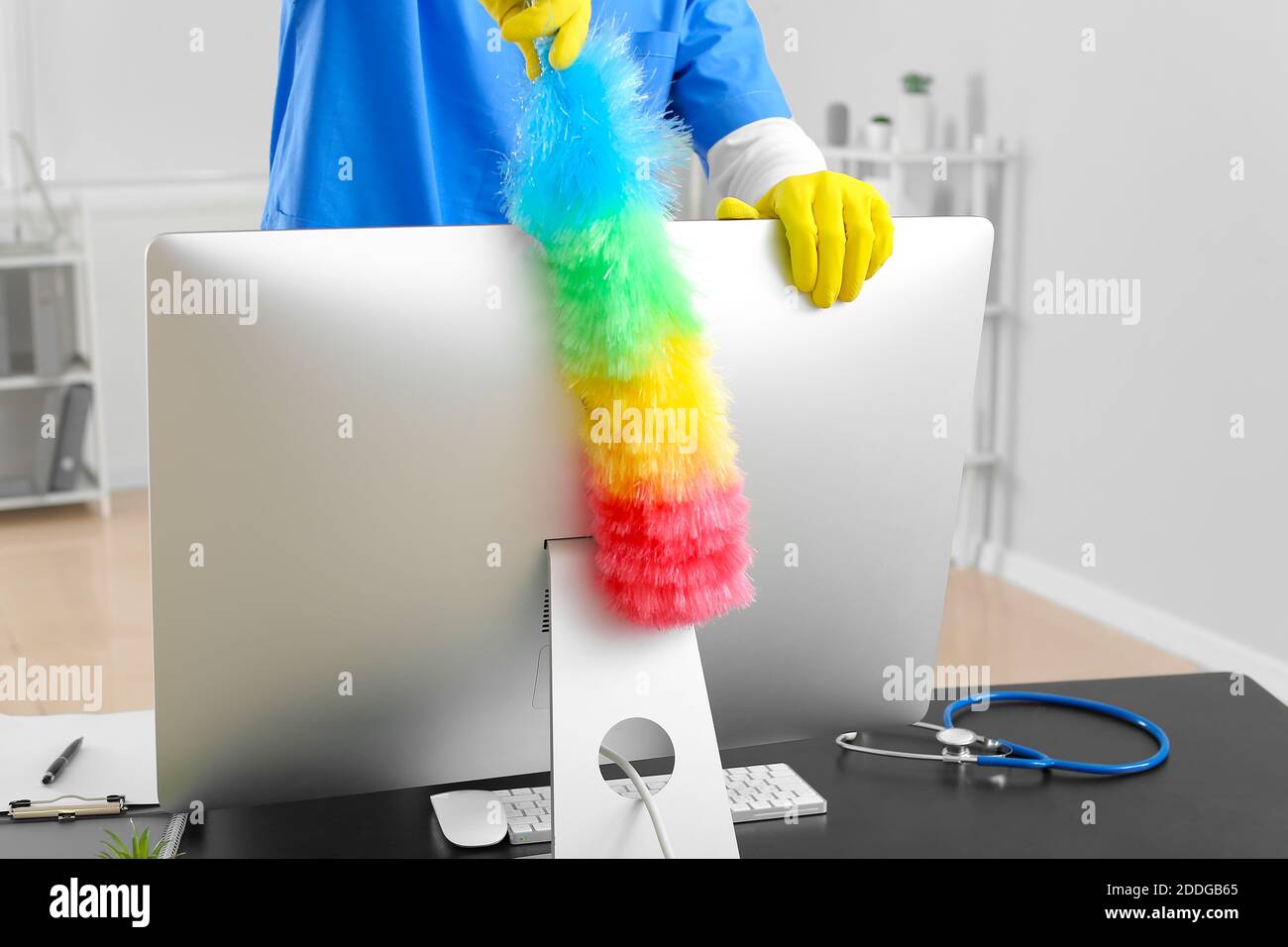 Male janitor cleaning computer in office Stock Photo - Alamy