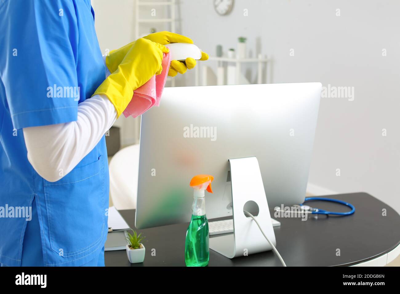 Male janitor cleaning computer in office Stock Photo - Alamy