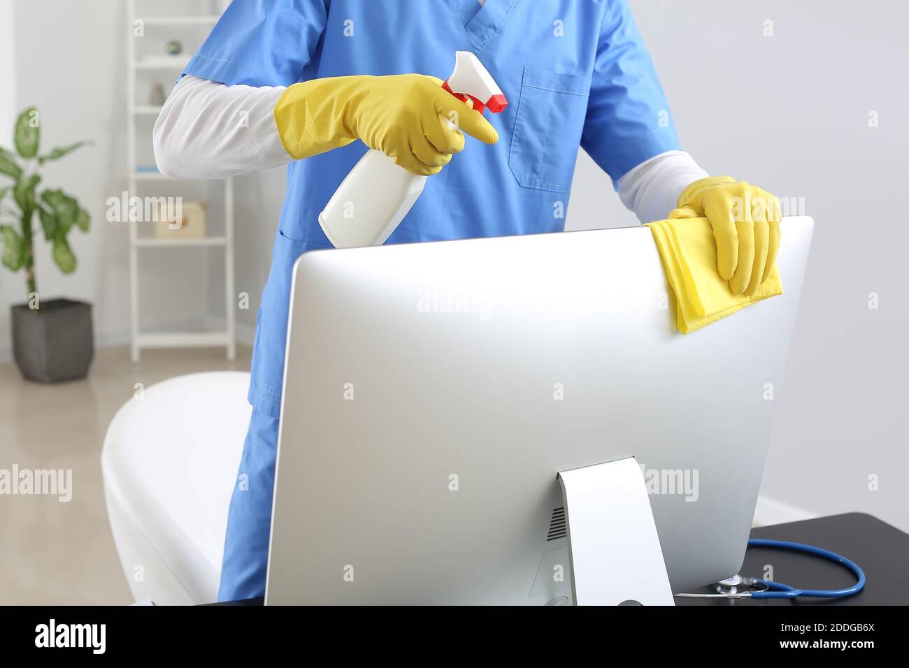Male janitor cleaning computer in office Stock Photo - Alamy