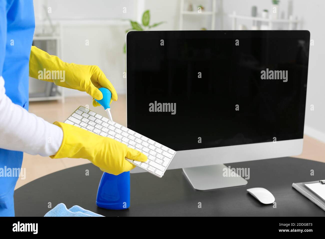 Male janitor cleaning computer in office Stock Photo - Alamy