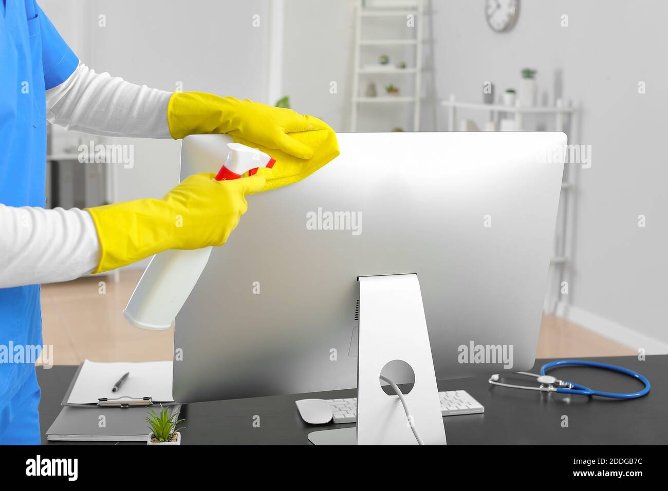 Male janitor cleaning computer in office Stock Photo - Alamy