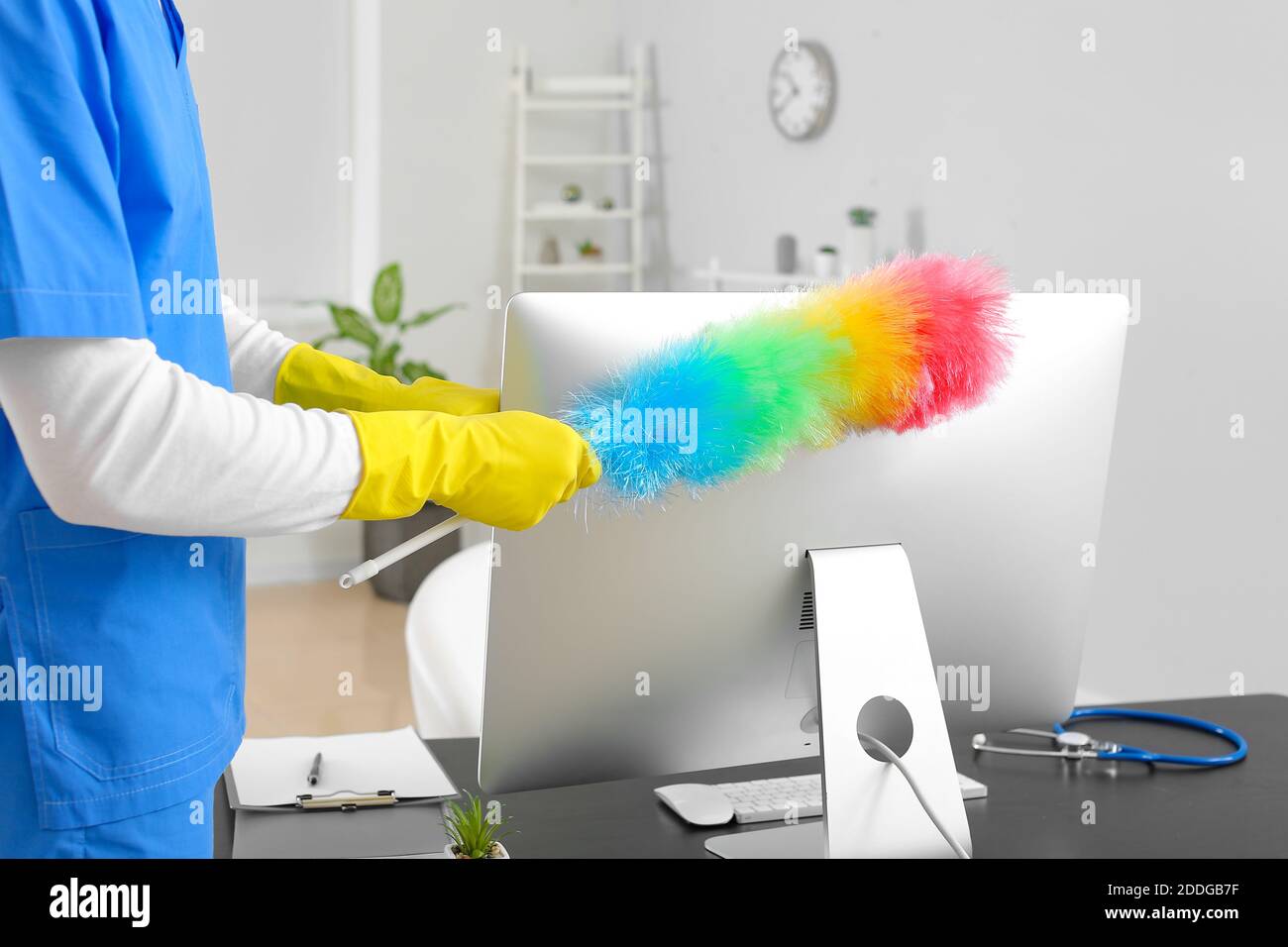 Male janitor cleaning computer in office Stock Photo - Alamy