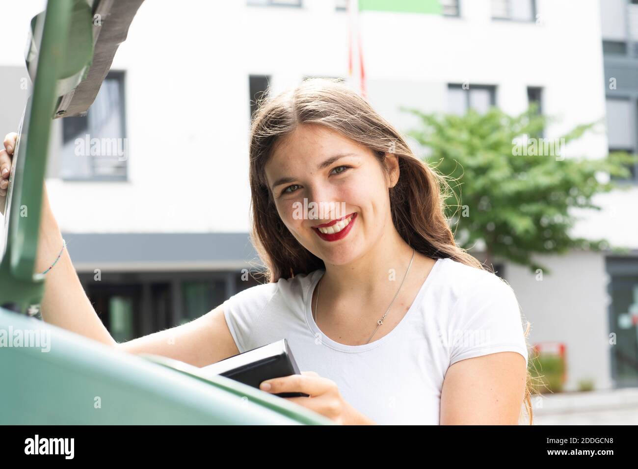 Young woman using recycling bin Stock Photo - Alamy