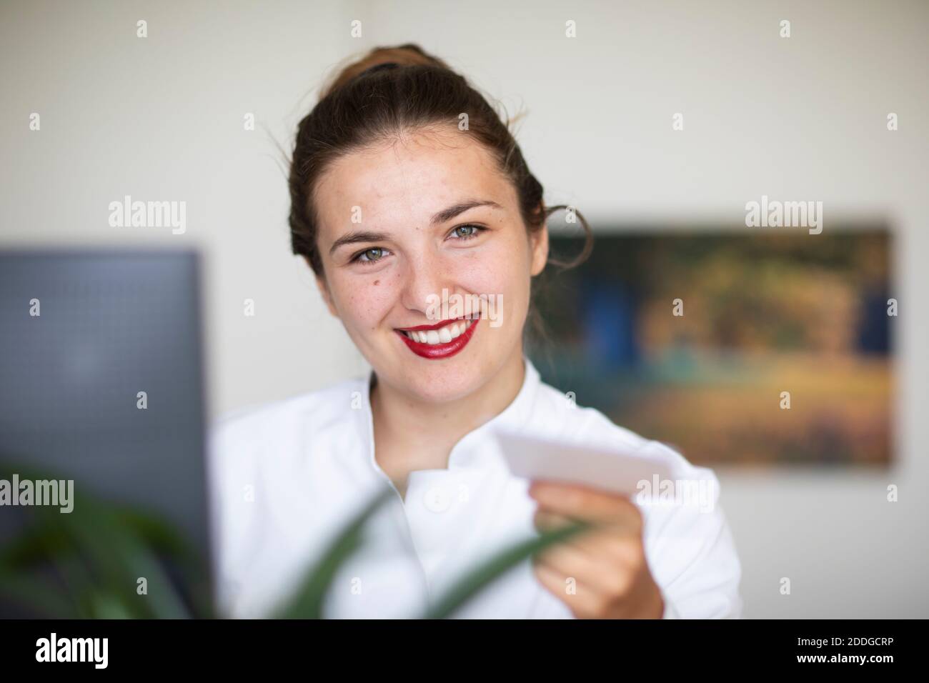 Young woman at computer, handing over card Stock Photo - Alamy