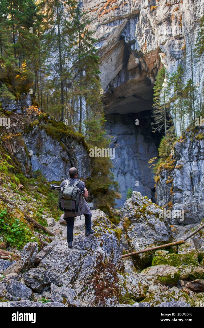 Professional nature photographer with heavy backpack, tripod and camera ...