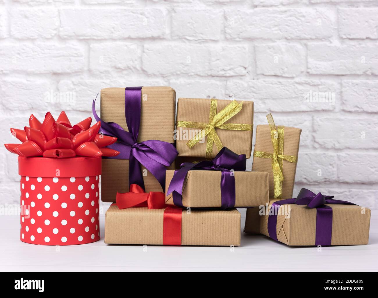 stack of various gift boxes on white brick background, festive backdrop ...