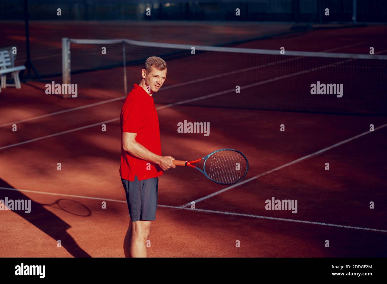 Tennis player standing with racket on tennis court Stock Photo - Alamy
