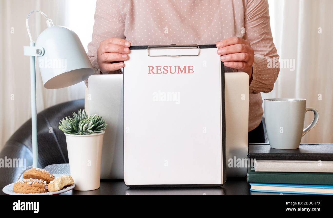 Woman hands holding resume application near her workplace with laptop ...