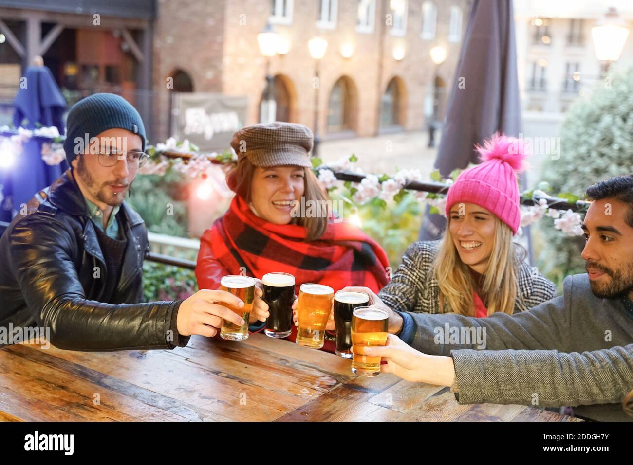 Group of millennial friends drinking and toasting beer at the bar in ...