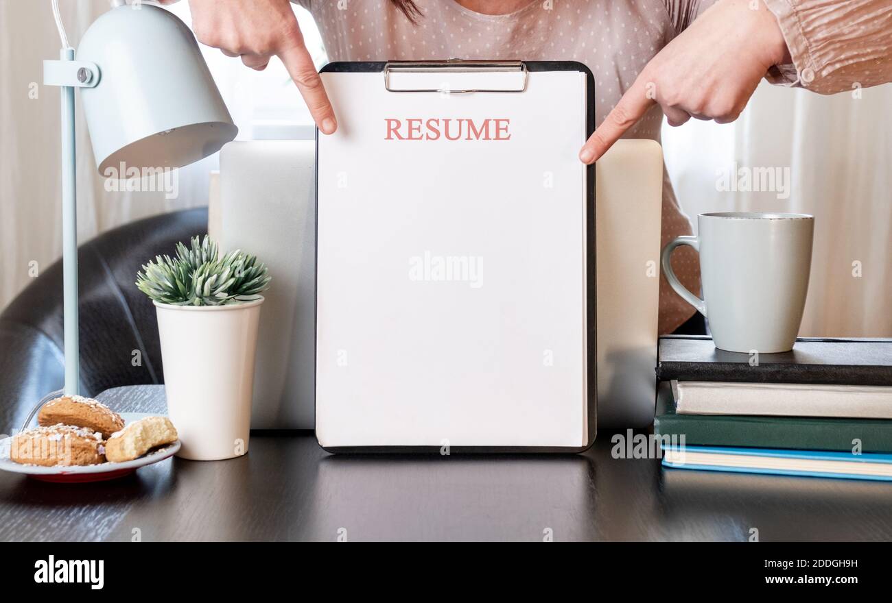 Woman hands holding resume application near her workplace with laptop ...