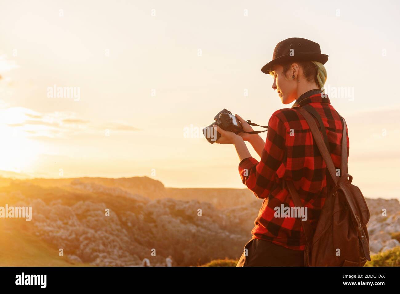 Side view of androgynous female traveler with professional photo camera ...