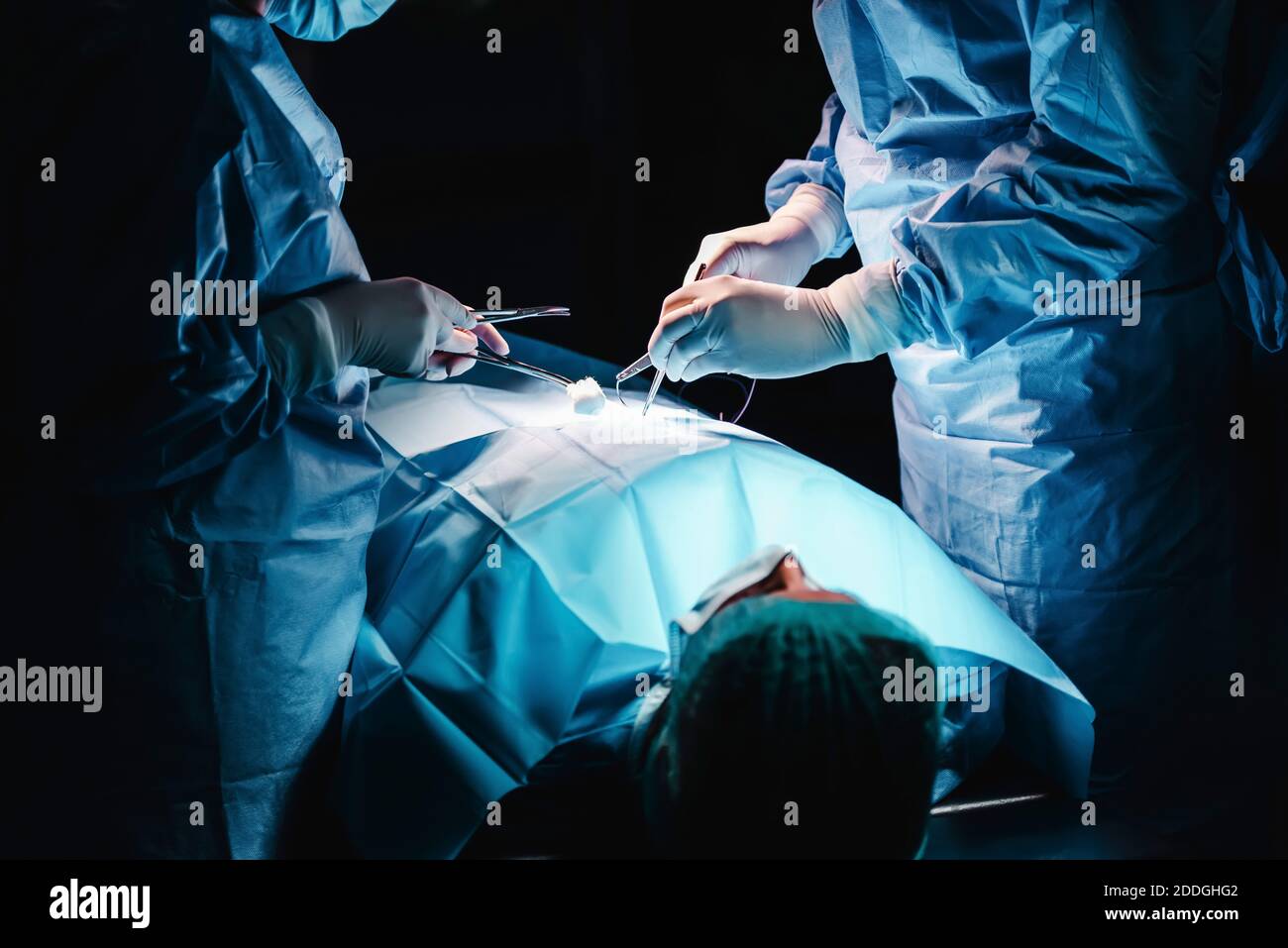 Crop anonymous surgeon and assistant with surgical tools and thread ...