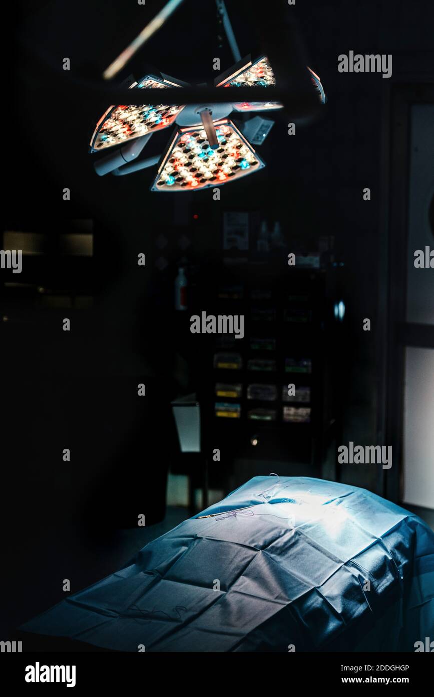 Interior of operating theater with surgical bed under glowing lights ...