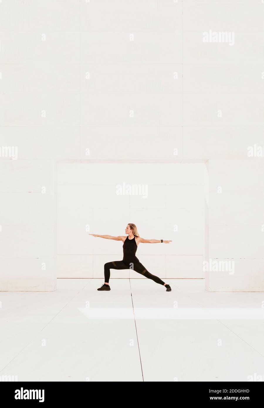 Full body side view of slim female in black sportswear performing ...