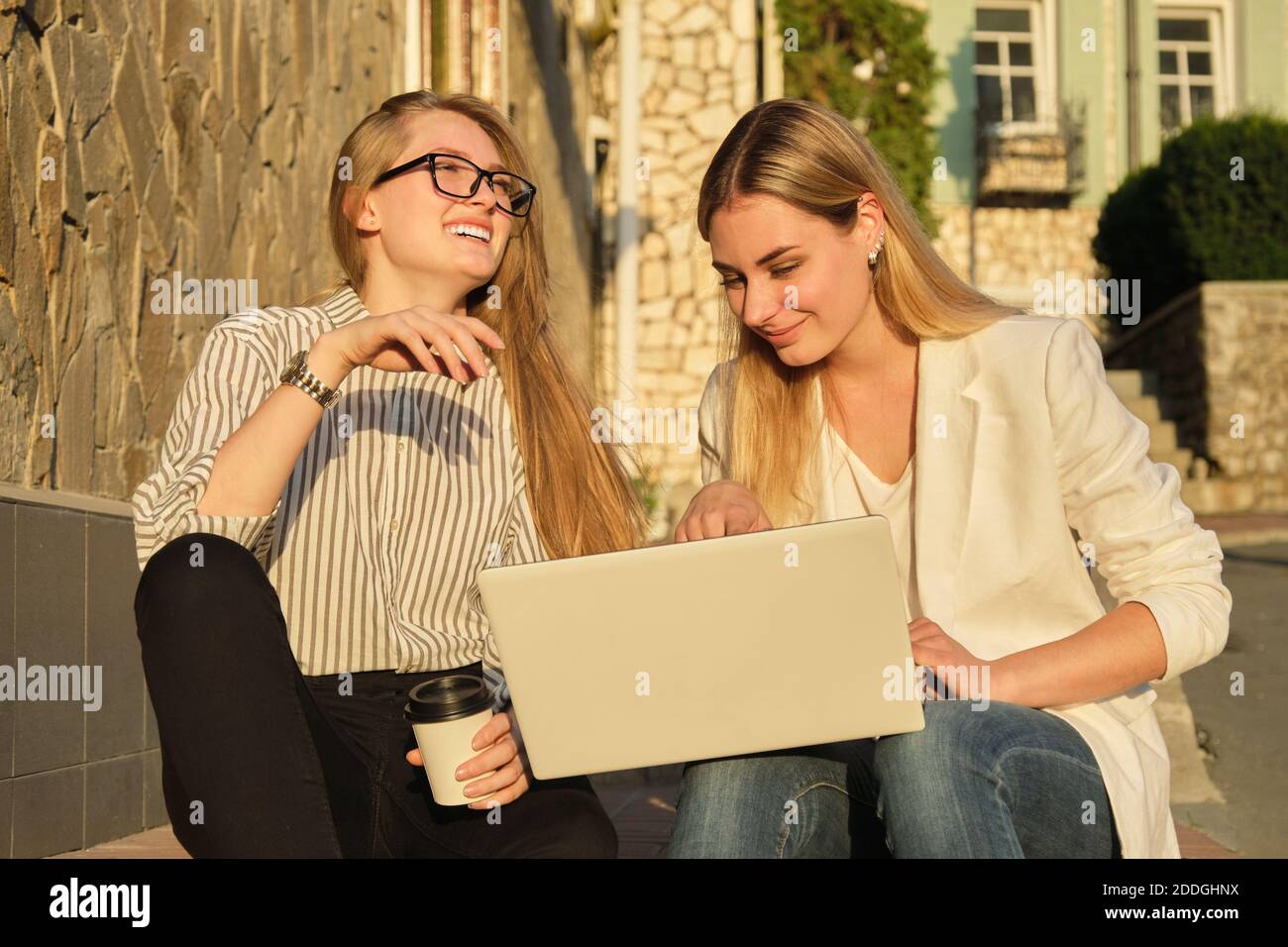 Two young beautiful women having fun looking into the laptop monitor ...