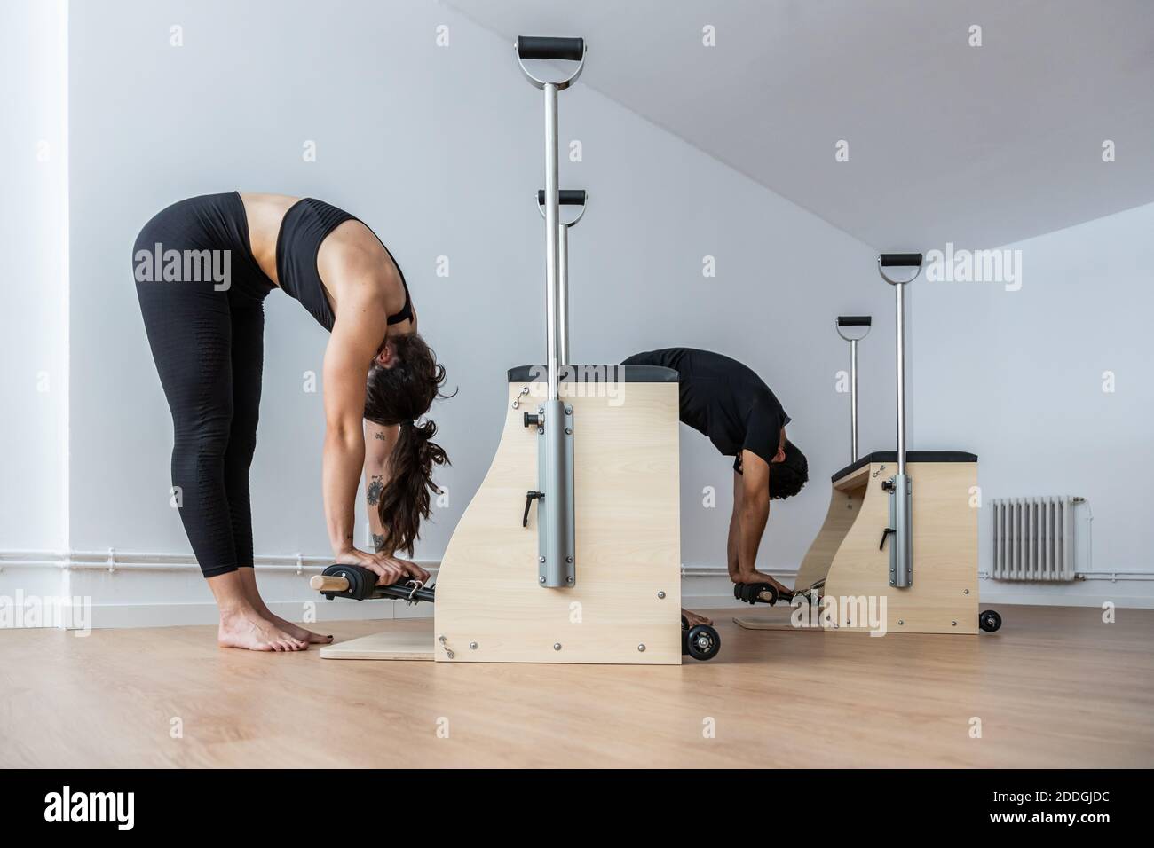 Side view of focused sportsWoman and sportsman stretching body on ...