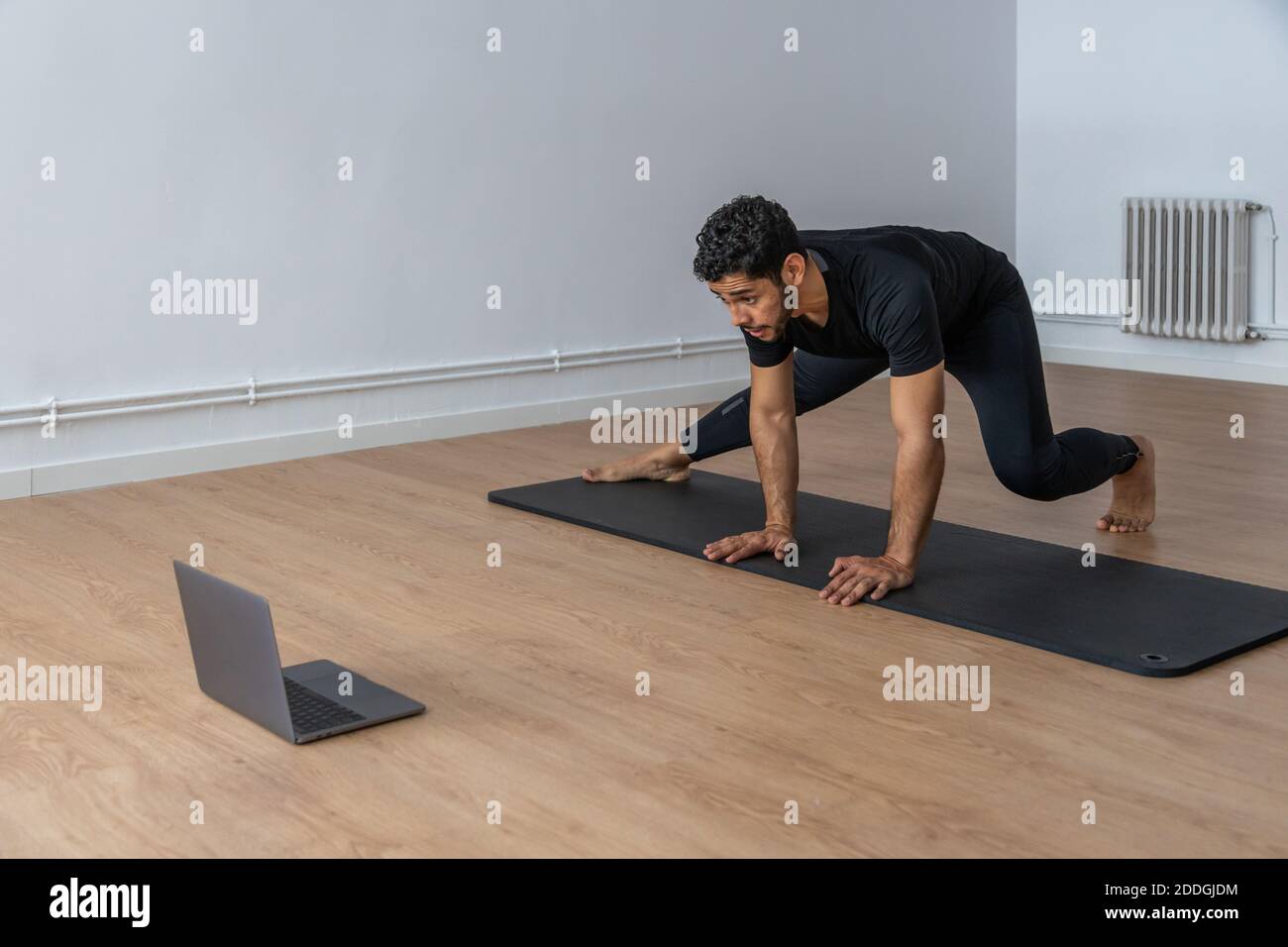 Concentrated ethnic male athlete practicing on mat during training ...