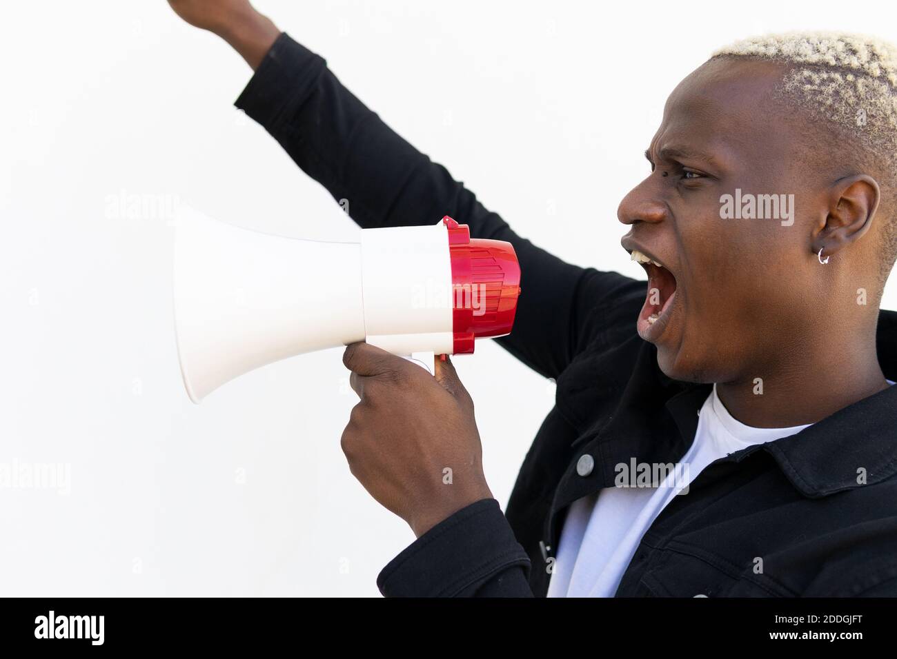 Side view of cheerful African American male shouting in loudspeaker ...