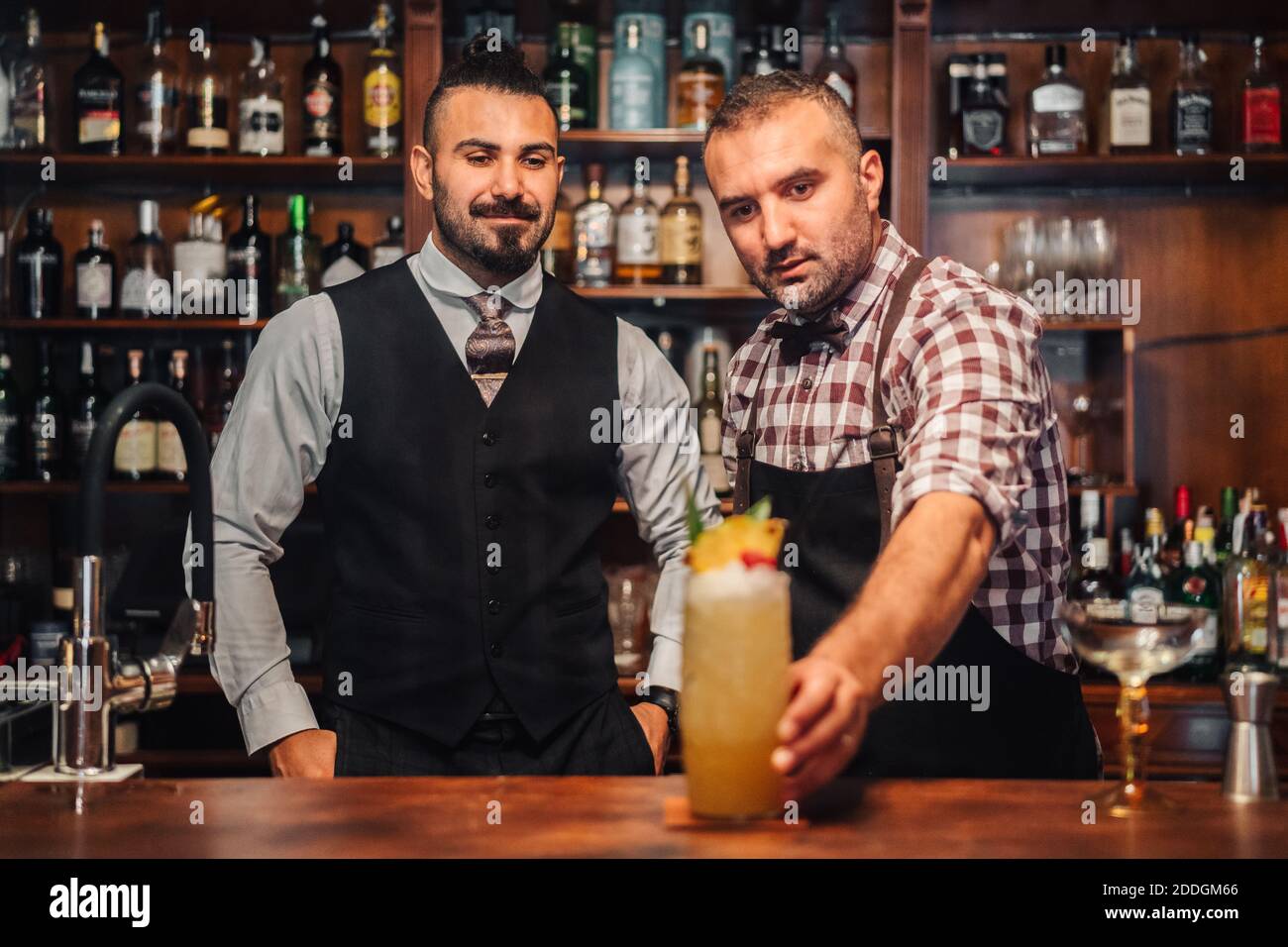 Bearded bartenders smiling while preparing fresh cocktails at counter ...
