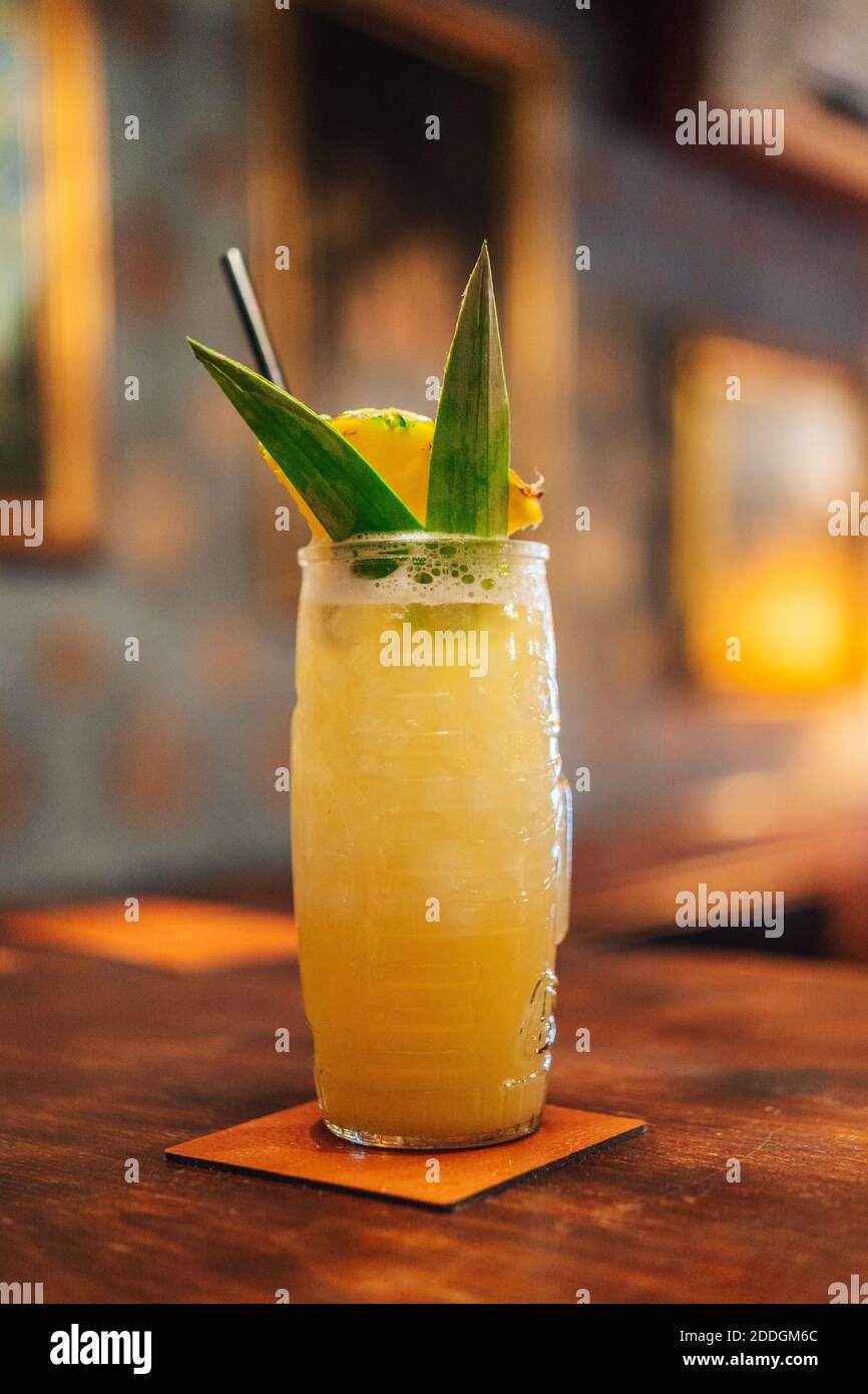 Glass cup of tropical cocktail with pineapple and leaves placed on ...