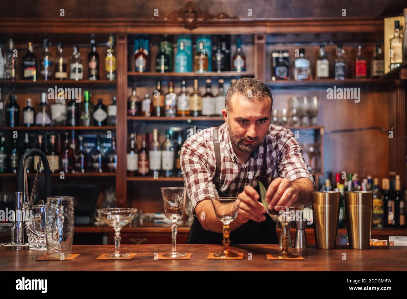 Middle aged man in apron and checkered shirt decorating glass of ...