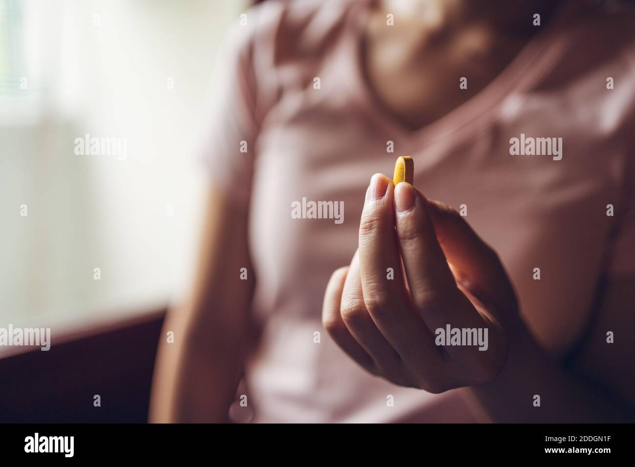 Crop unrecognizable healthy female showing bright yellow vitamin pill ...