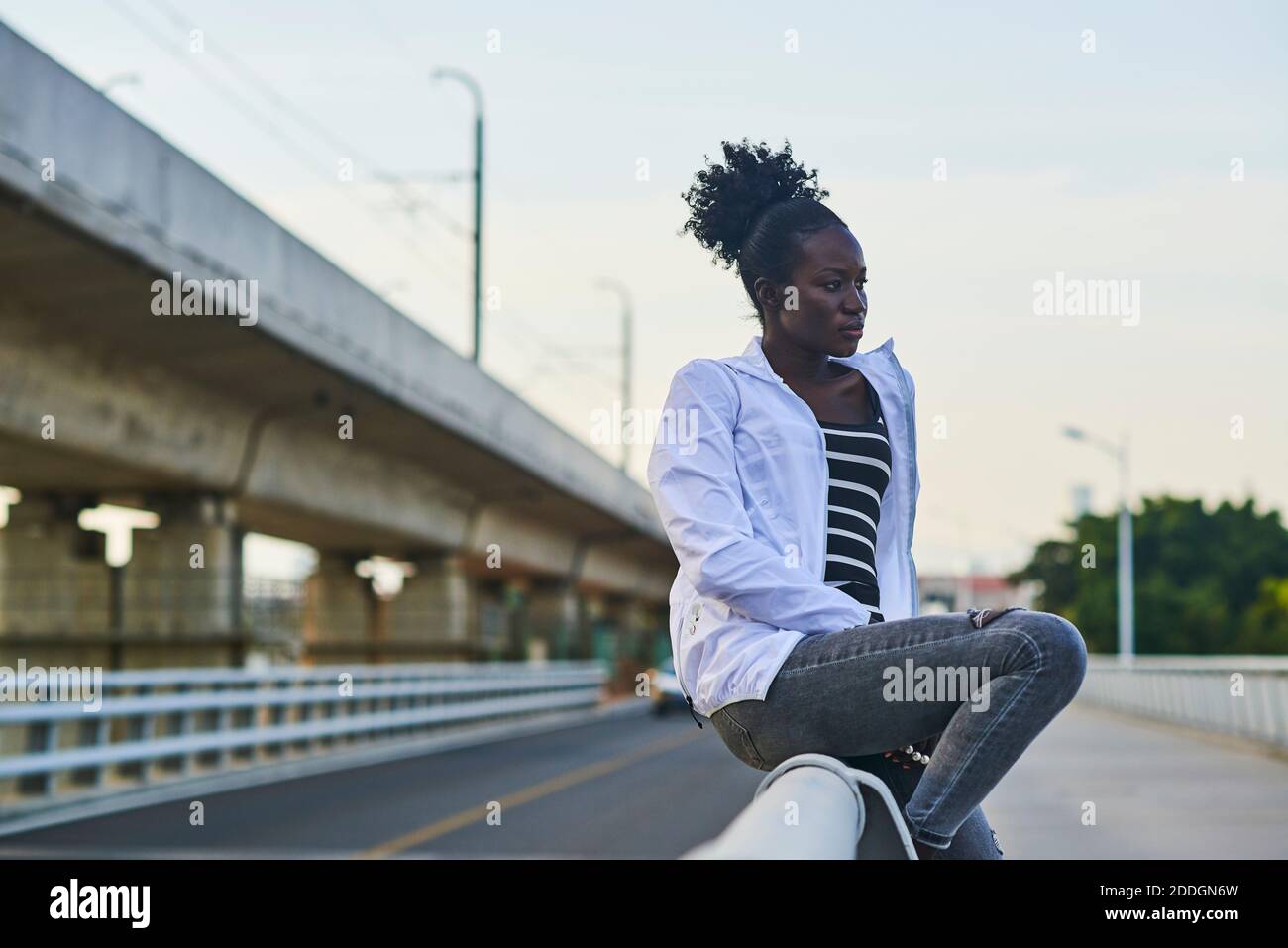 Side view of young African American female in casual wear sitting on ...