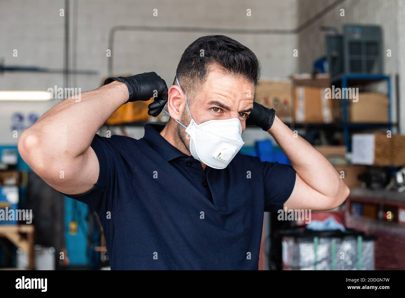 Male employee putting white face mask for work in garage Stock Photo ...