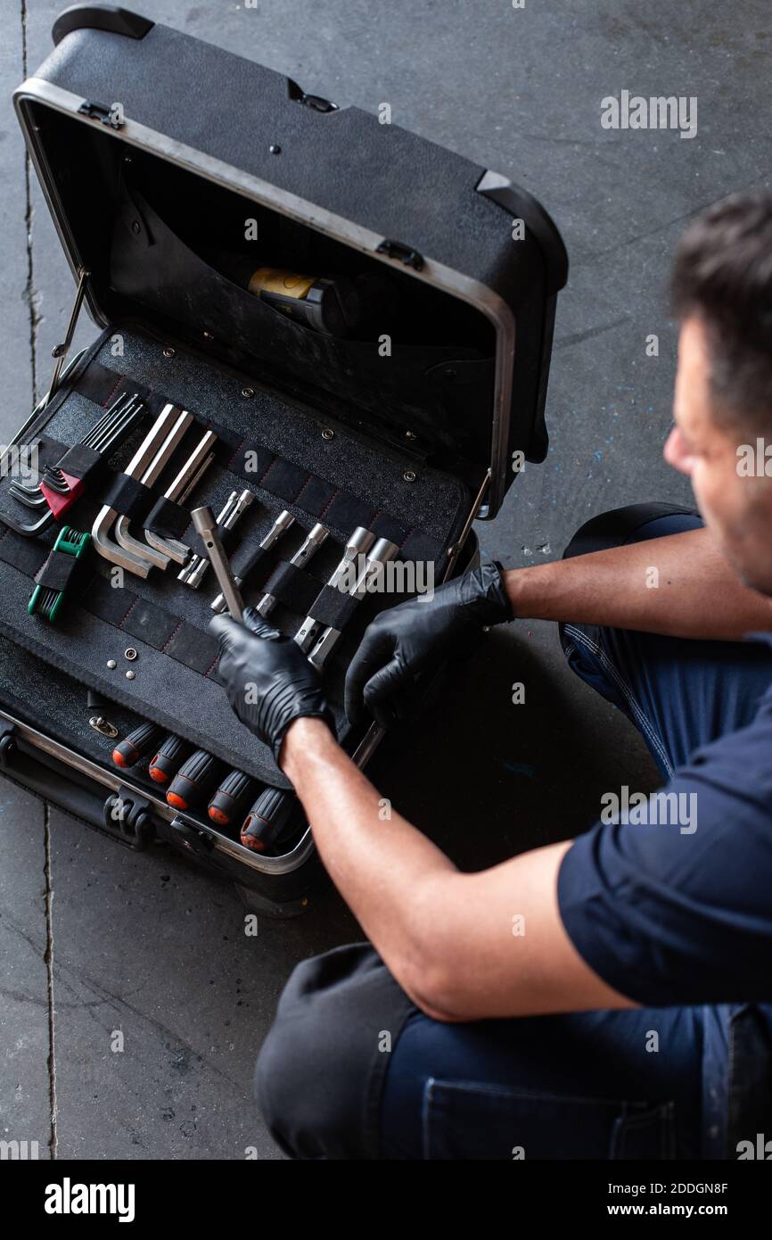 From above male technician picking screwdriver bits from tool box while ...