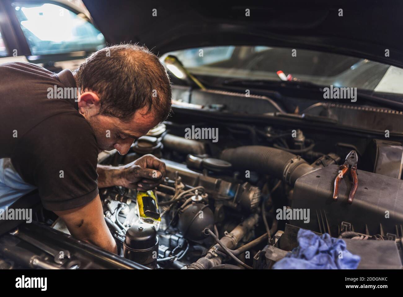 Side view of adult male mechanic illuminating engine with flashlight ...