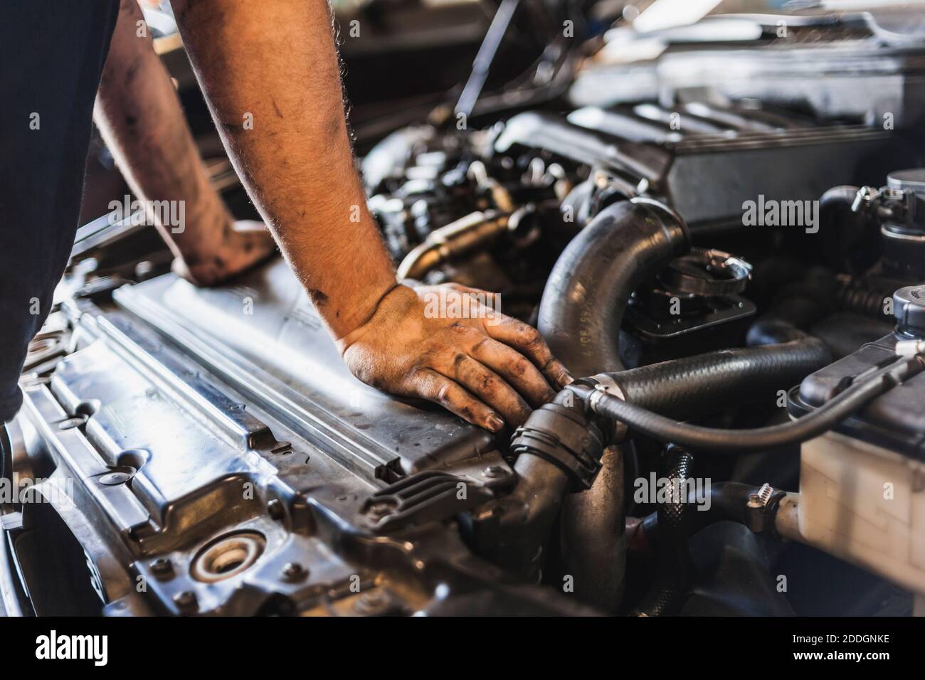 Cropped unrecognizable male mechanic with greasy hands checking motor ...