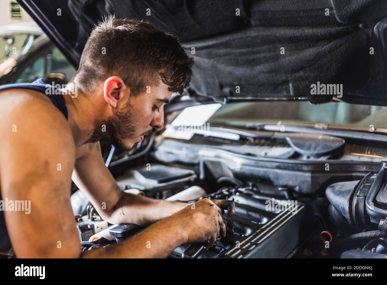 Side view of technician with greasy hands turning screw with spanner ...