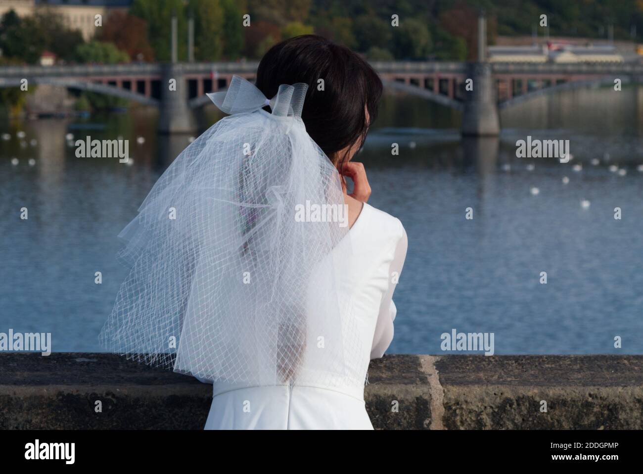 The bride admires Prague from Charles Bridge. Girl in a wedding dress ...