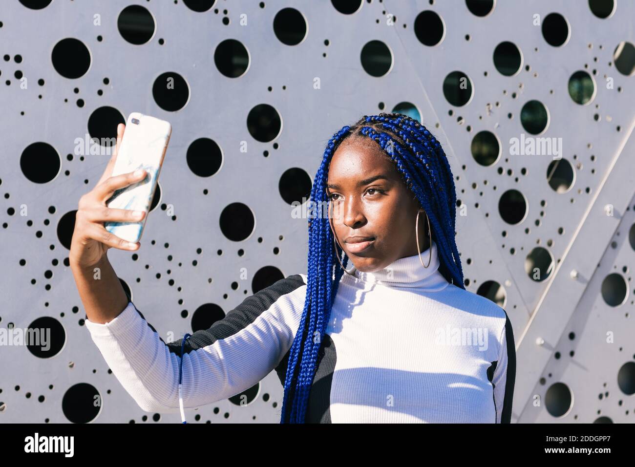Determined African American female with blue braids standing in urban ...