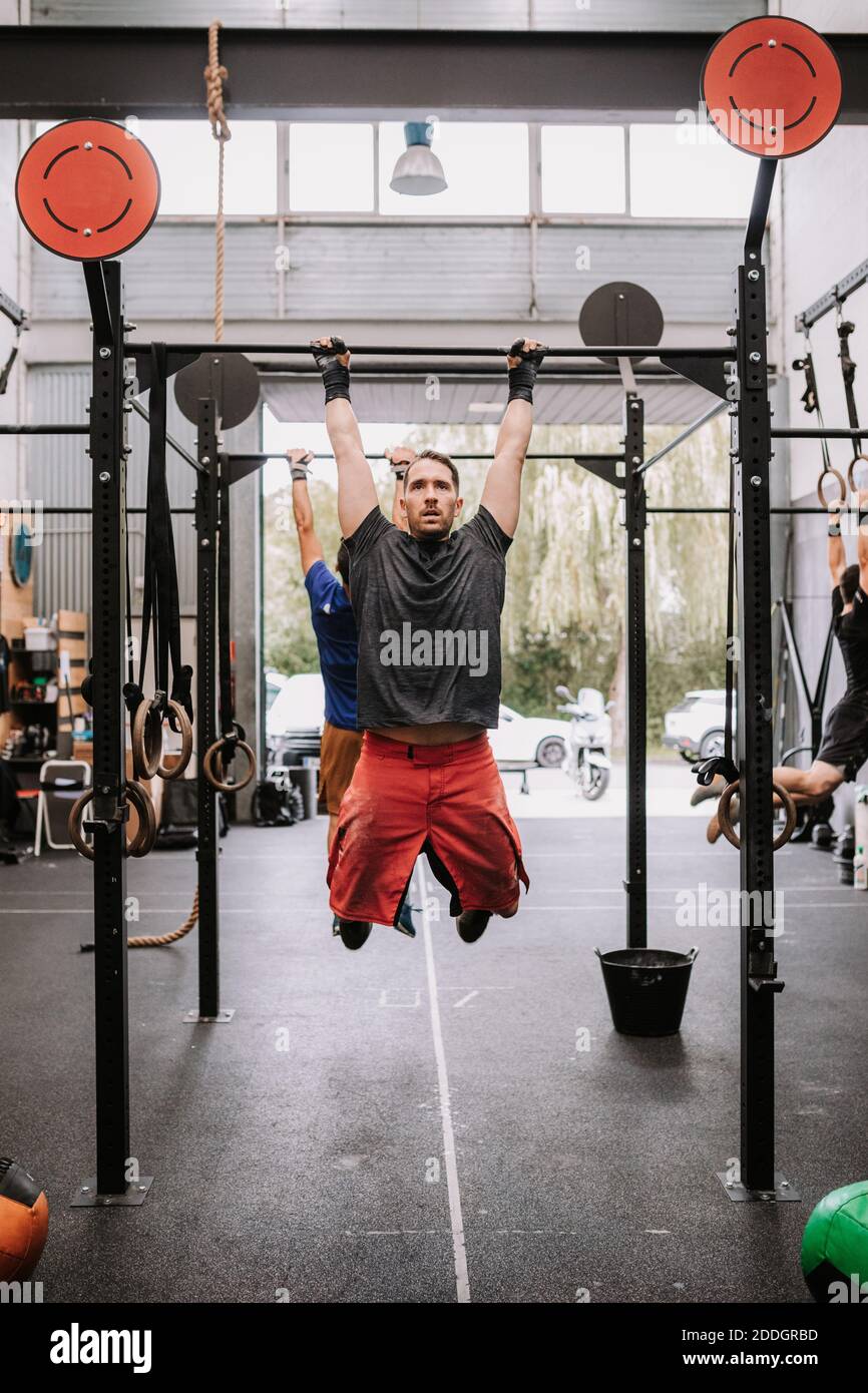Determined male athlete making effort and pulling up on bar during ...