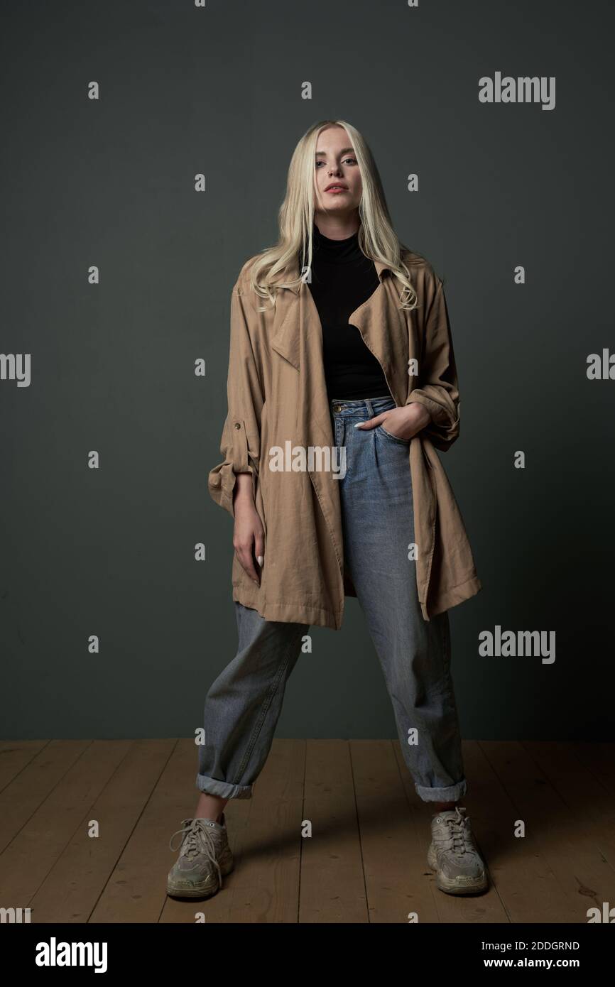 Side view of young female surfer in wetsuit with surfboard standing ...