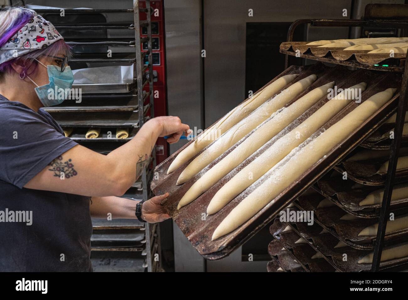 Side view of focused female baker in protective mask making notches on ...