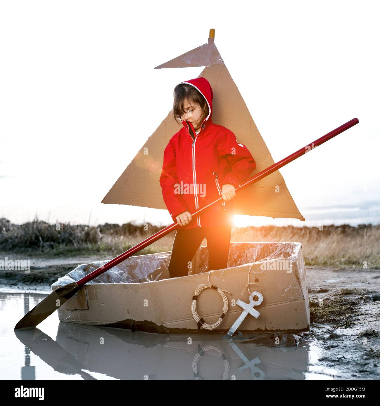 Cute kid with paddle playing in handmade cardboard boat while ...