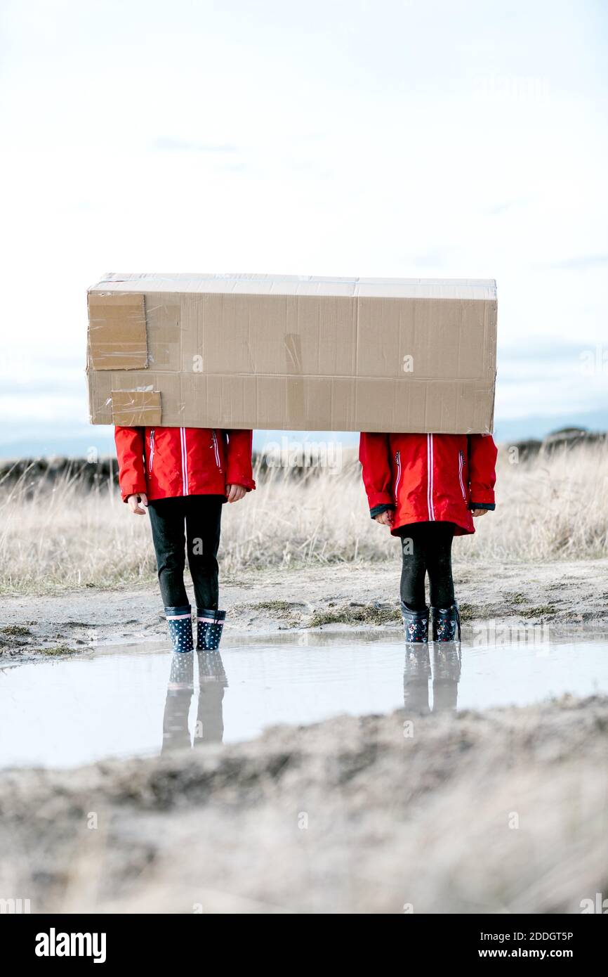 Anonymous children in rubber boots and raincoats standing in puddle and ...
