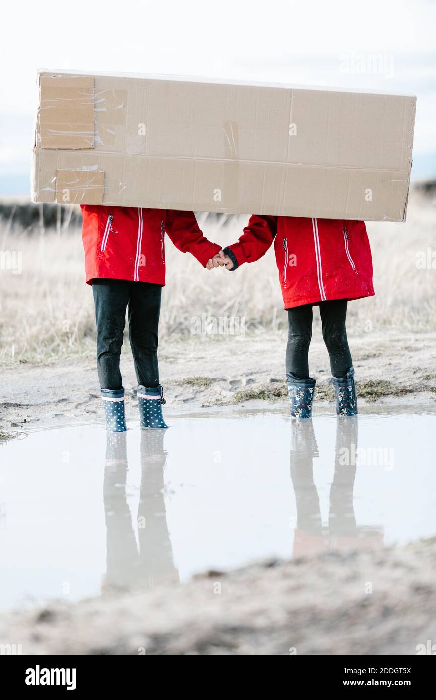 Anonymous children in rubber boots and raincoats standing in puddle and ...